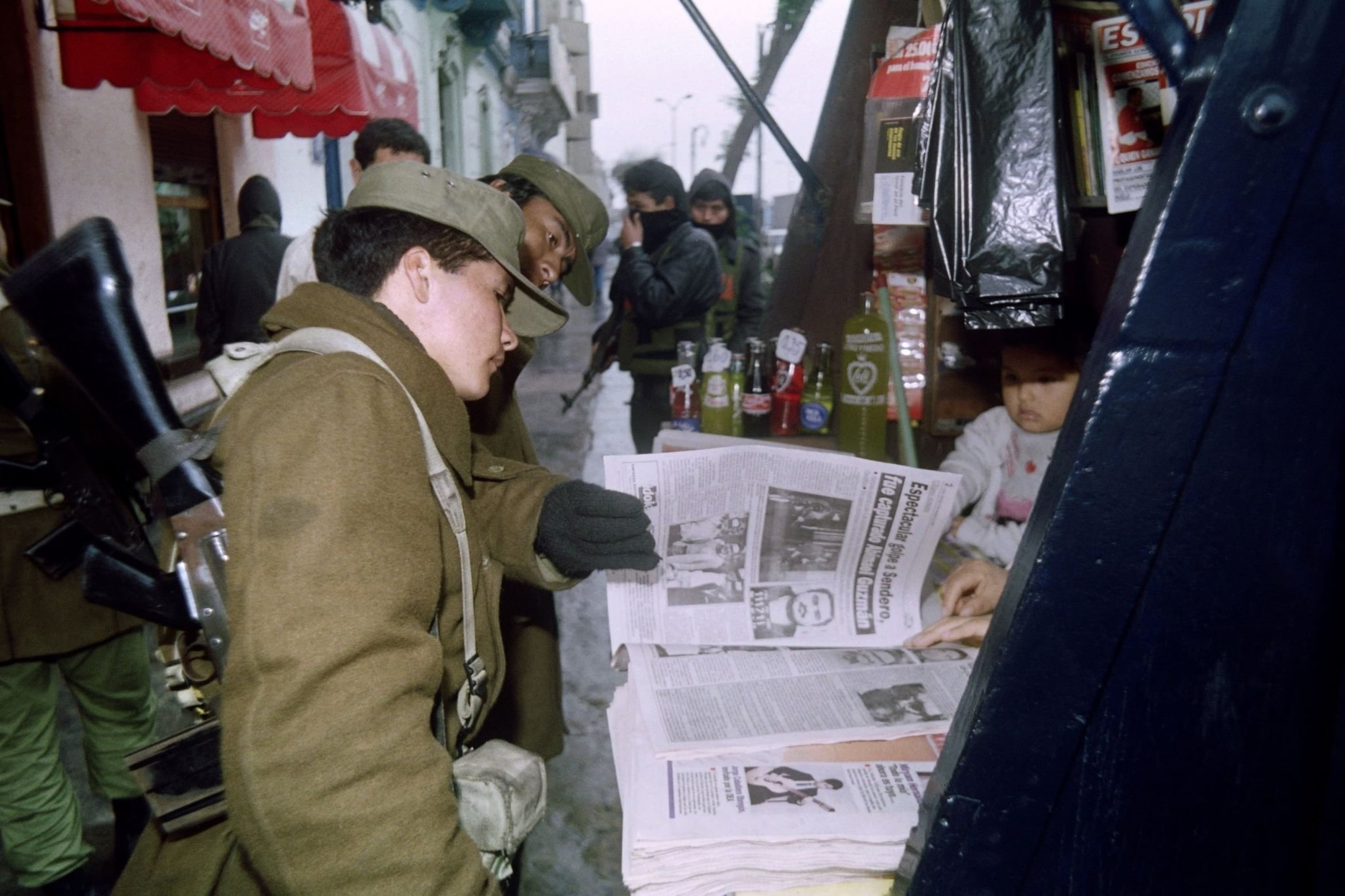 Peruvian Army soldiers check the headlines as they report the captur of ...