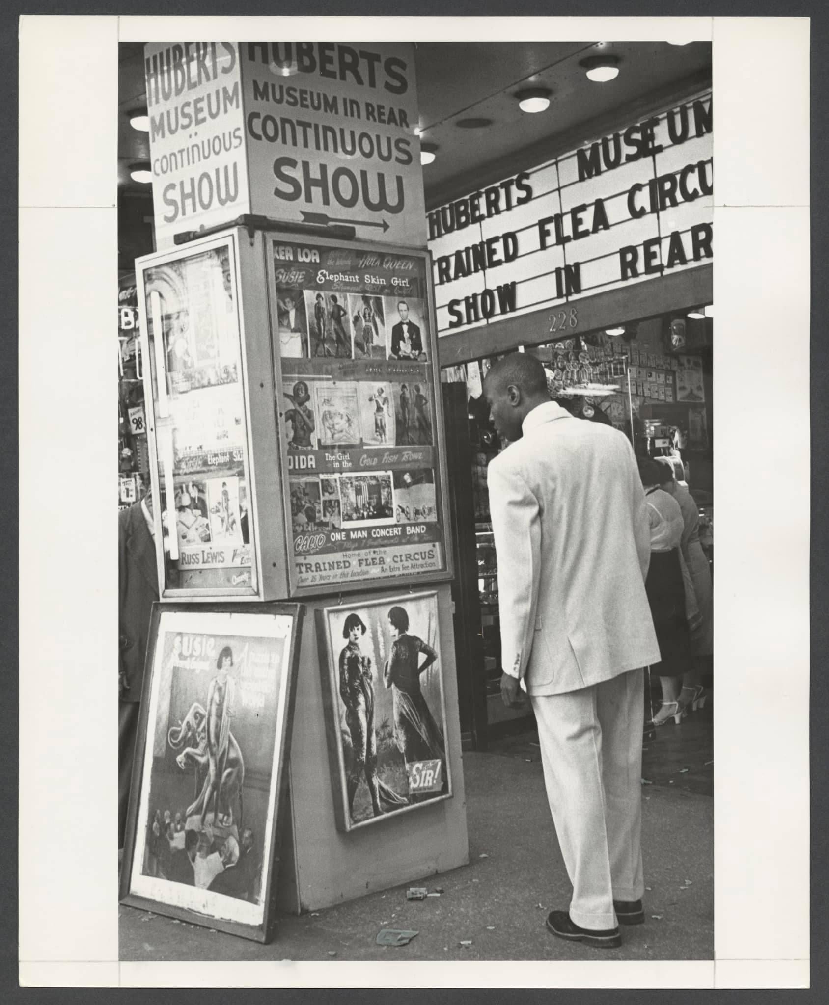 A man reading advertisements under the marquee at Hubert’s Museum and ...